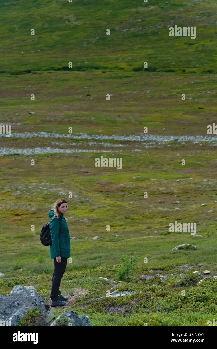 Active female hiker with backpack looking at the camera. In green ...