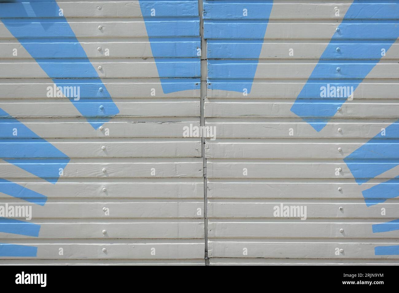 A close-up of a navy blue and white door depicting a sun with its rays ...