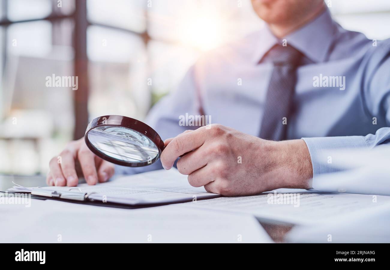 Businessman looking through a magnifying glass to documents Stock Photo ...
