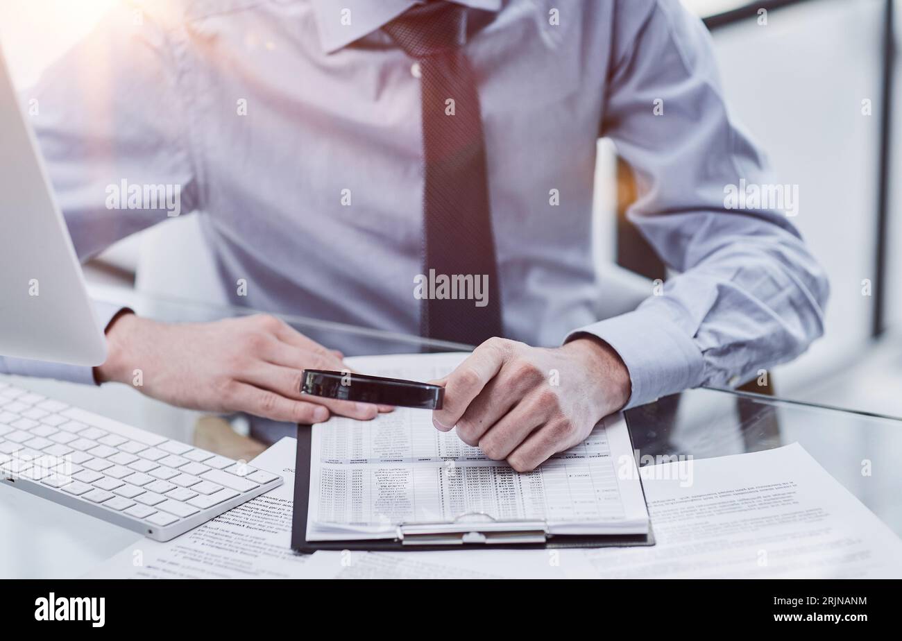 Businessman looking through a magnifying glass to documents Stock Photo ...