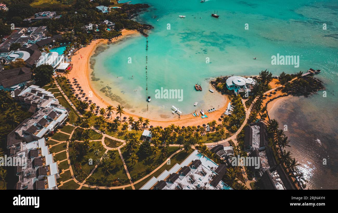 A scenic aerial view of a beach with green palm trees and hotels ...