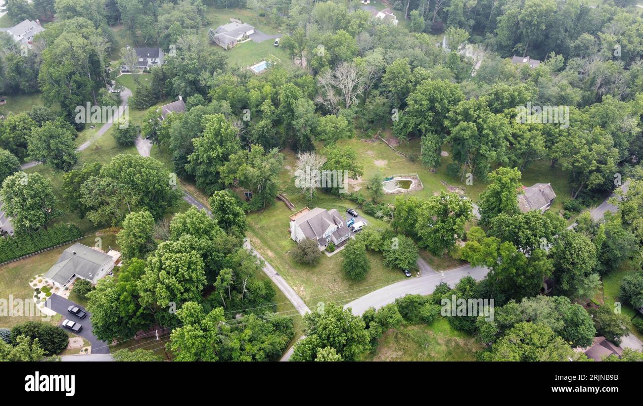 A two-story home situated on a corner lot surrounded by lush greenery ...