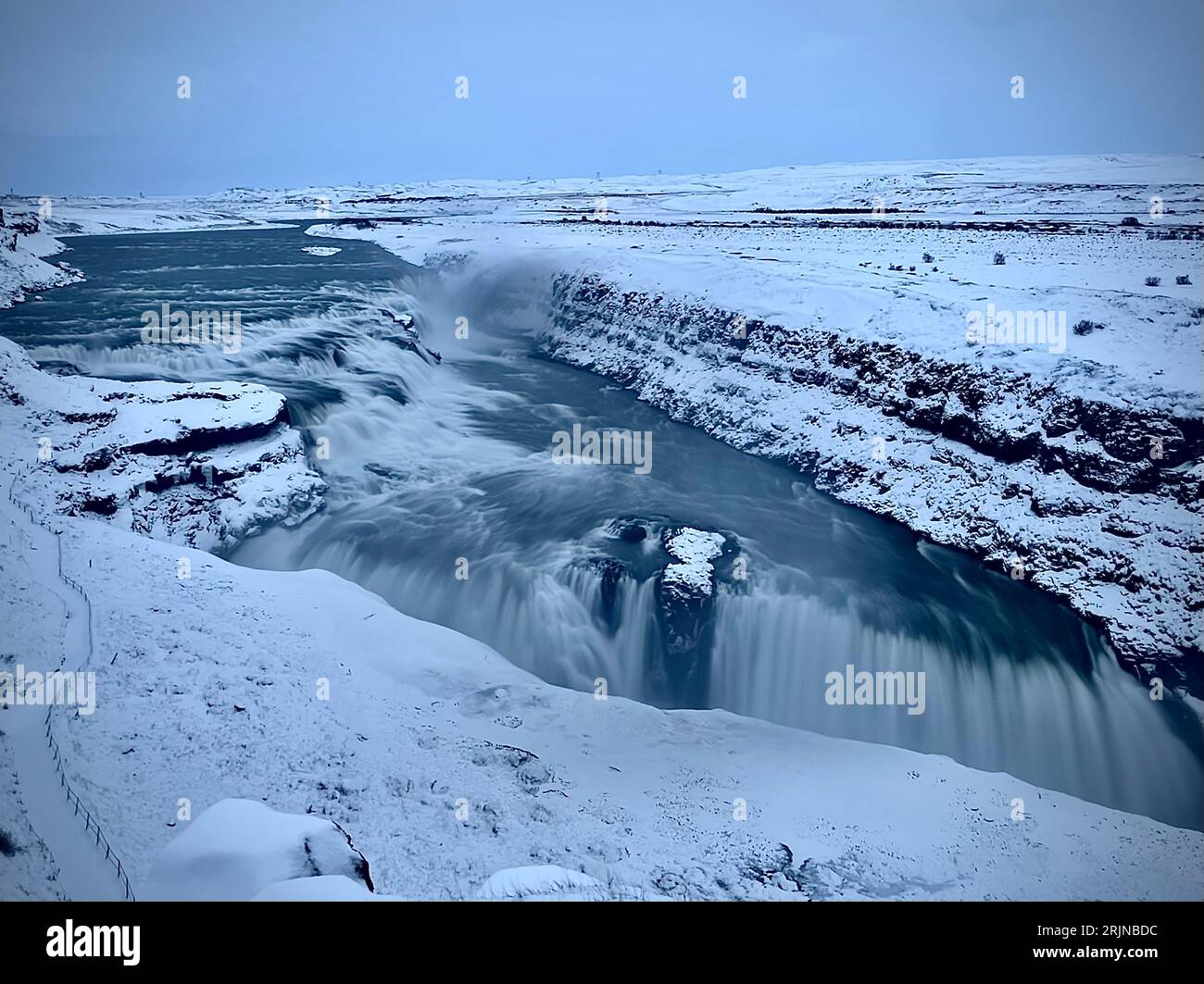 An aerial view of a majestic waterfall cascading down a snow-covered ...