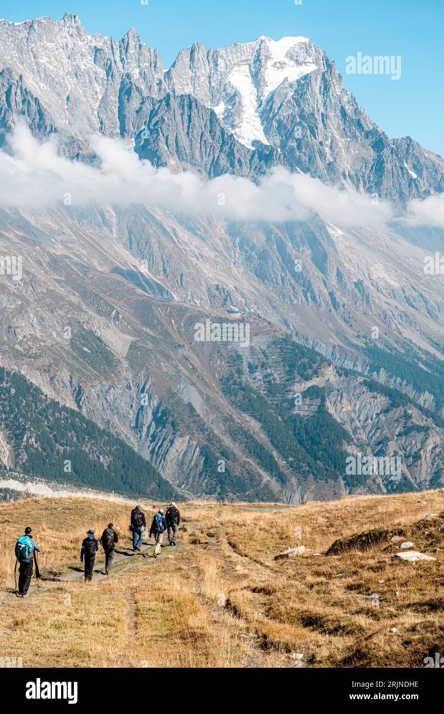 A diverse group of individuals ascending a mountain path, with a rugged ...