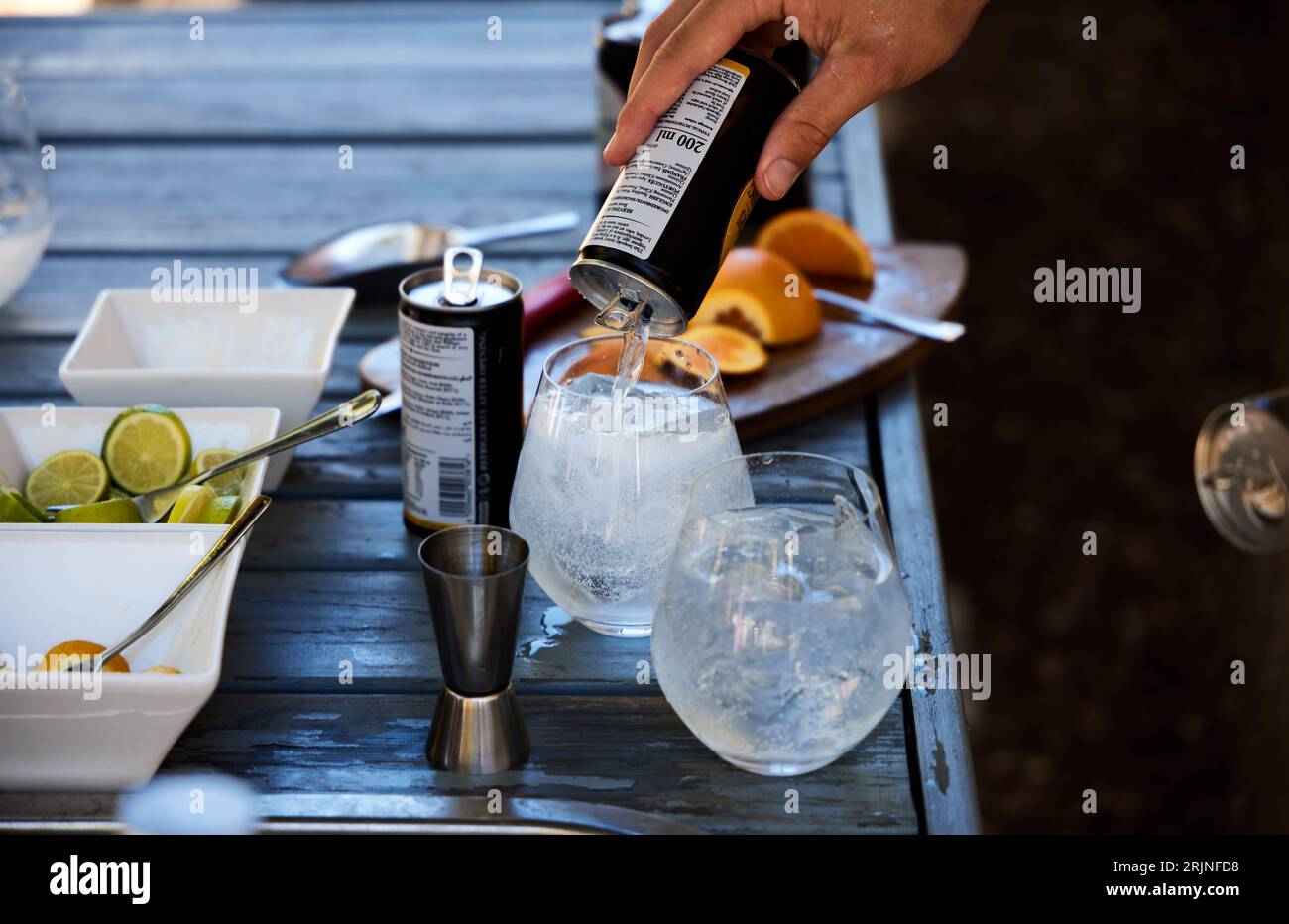 A young man standing at a bar table, expertly mixing drinks in two ...