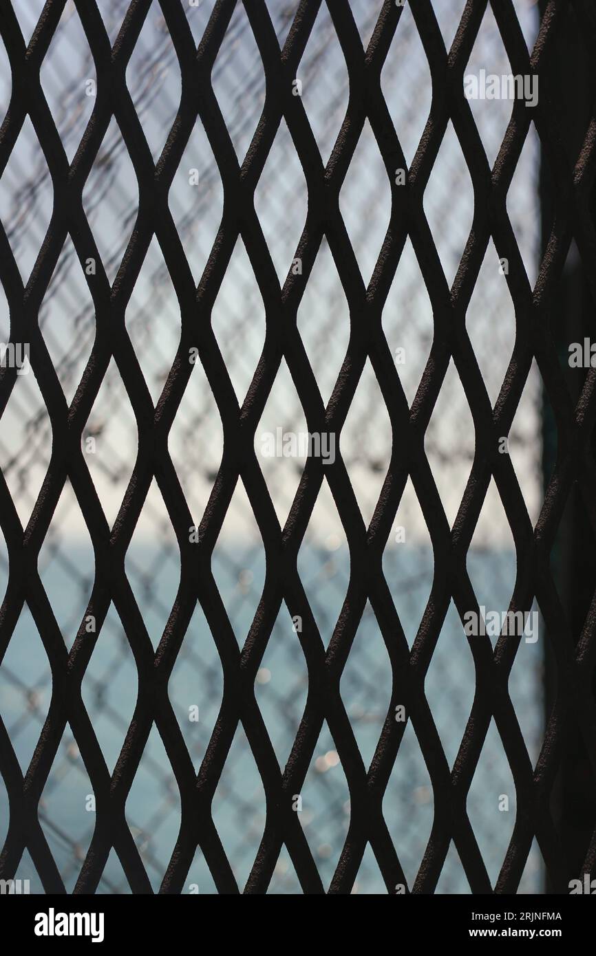 A common industrial chain link metal fence with a repeating pattern ...