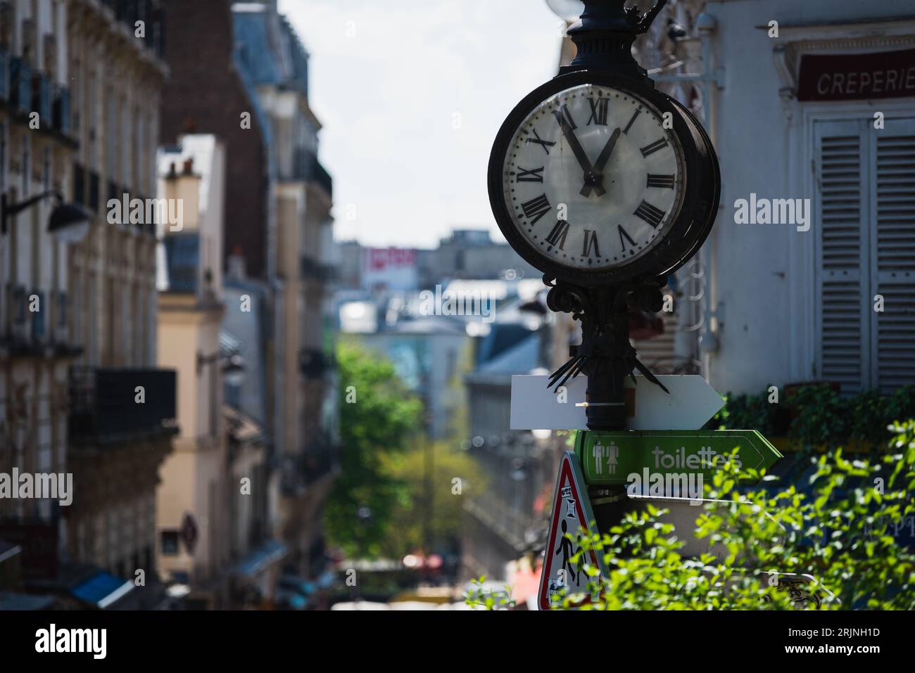 A close-up of an outdoor street clock with a blurry background in ...