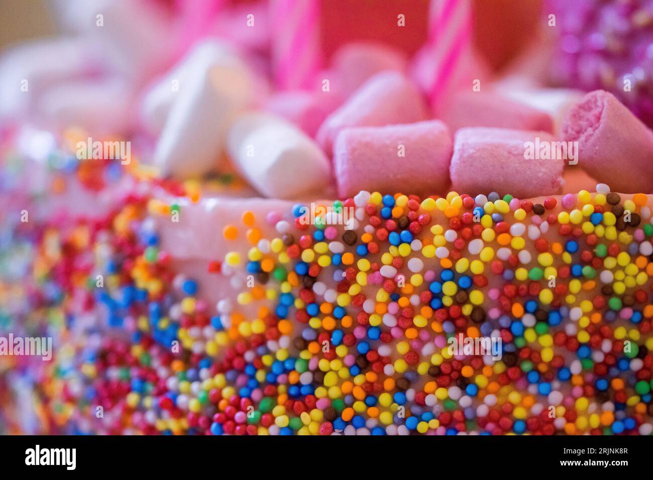 A pink-themed birthday cake, decorated with pink and white marshmallows ...