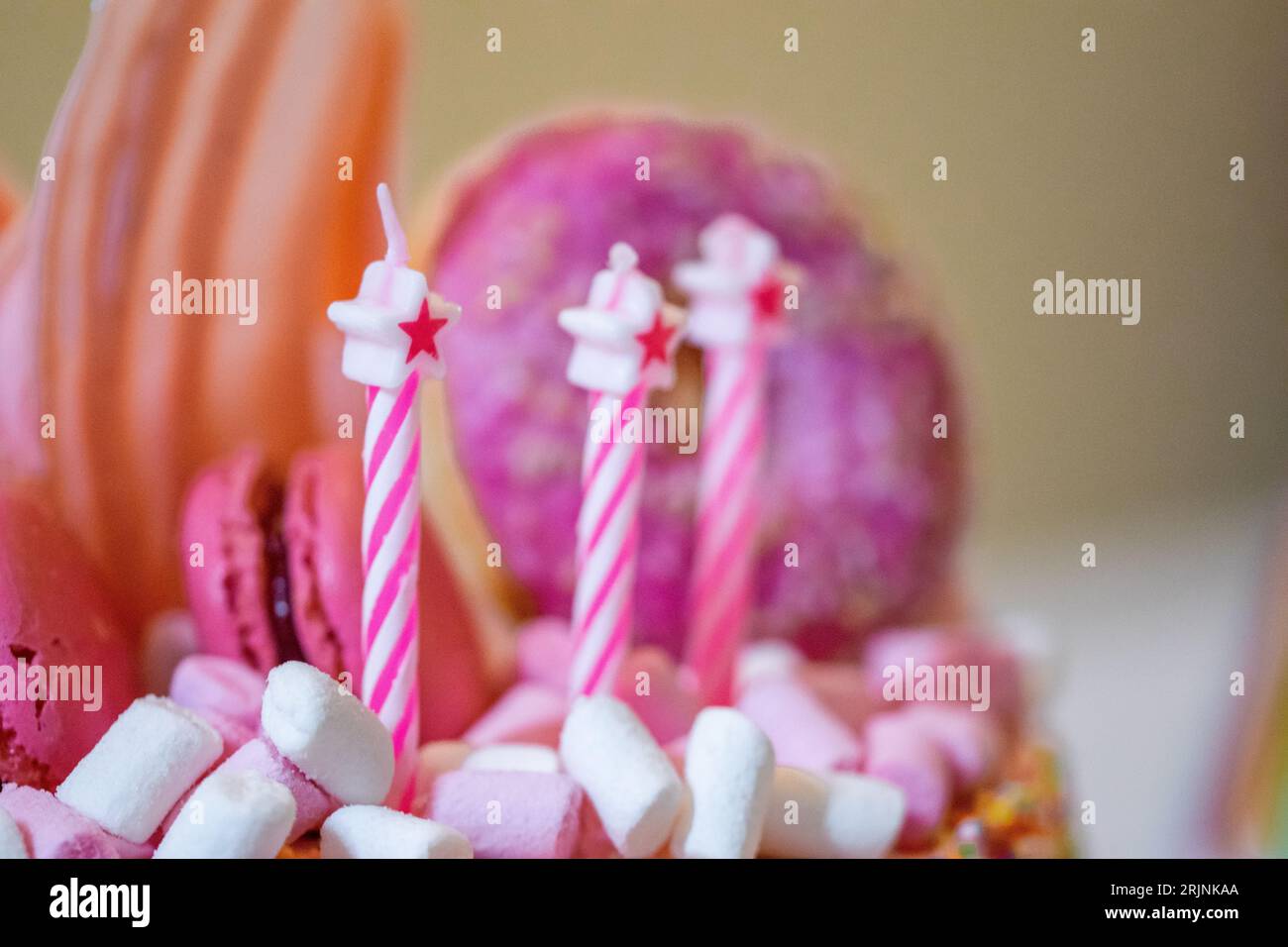 A pink-themed birthday cake, decorated with pink and white marshmallows ...