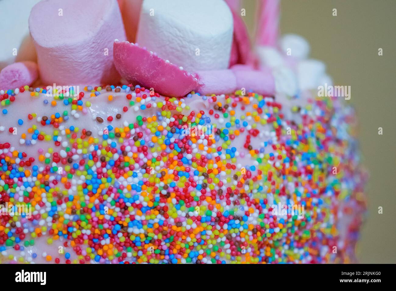 A pink-themed birthday cake, decorated with pink and white marshmallows ...