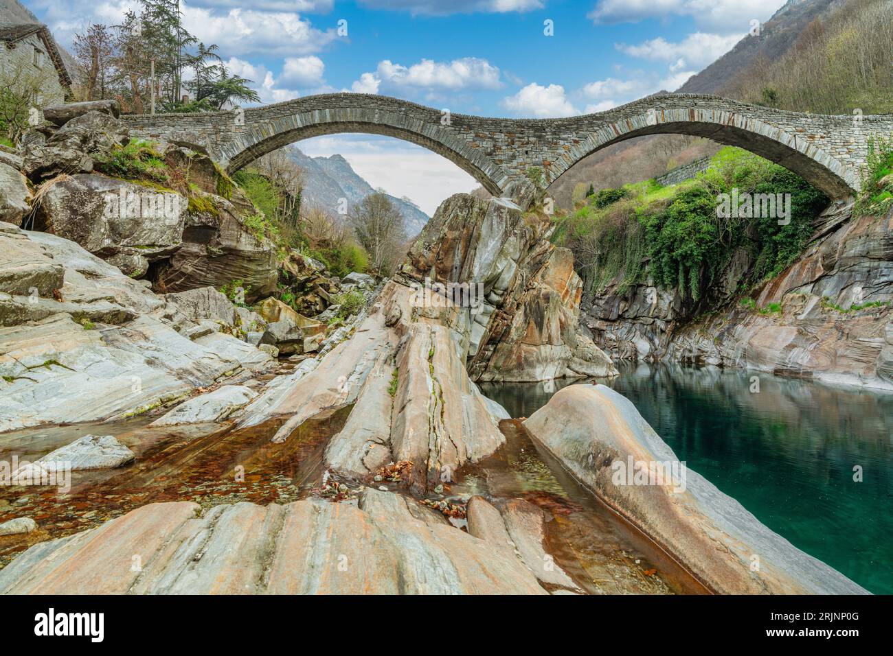 A scenic stone bridge crossing a tranquil river and lush trees in the ...