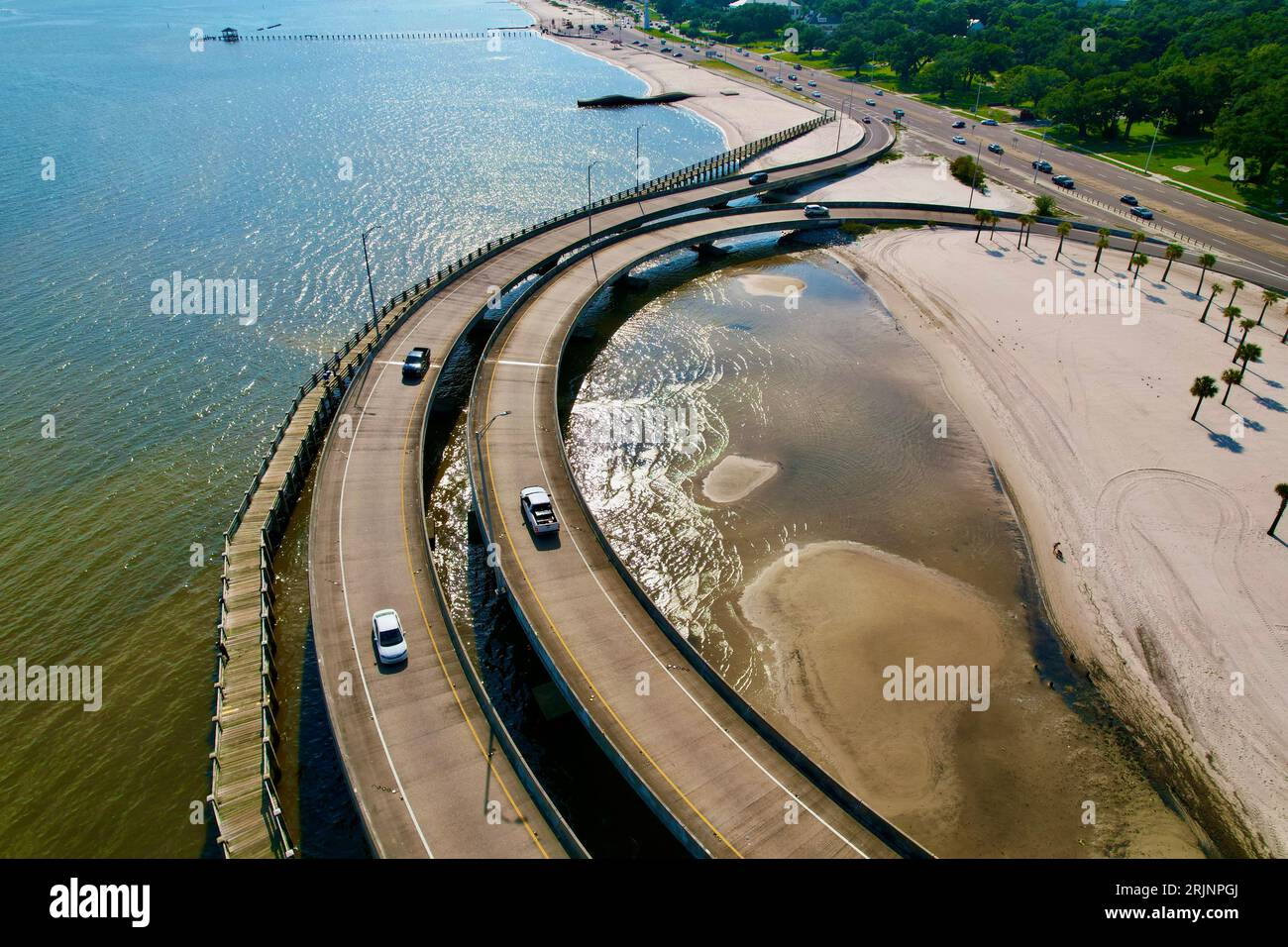 Multiple cars driving along a highway bridge, which is elevated above ...