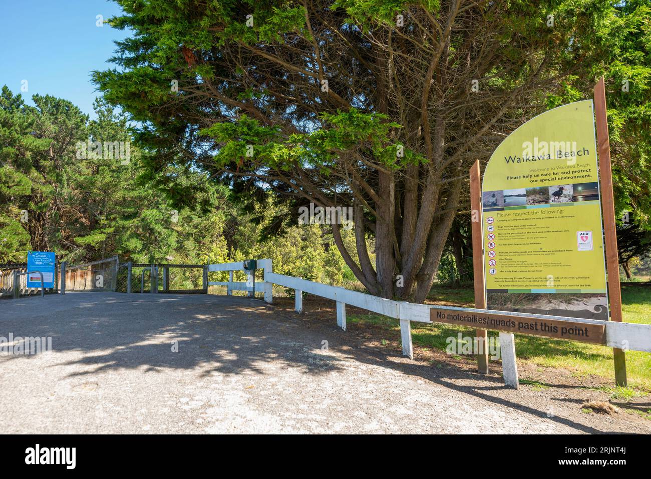 A wooden fence with a bright blue Waikawa Beach sign on a sunny day ...