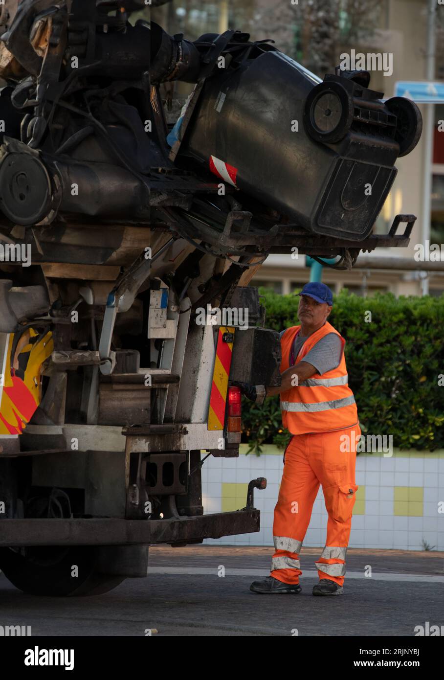 garbage collector loads garbage on the truck Stock Photo - Alamy
