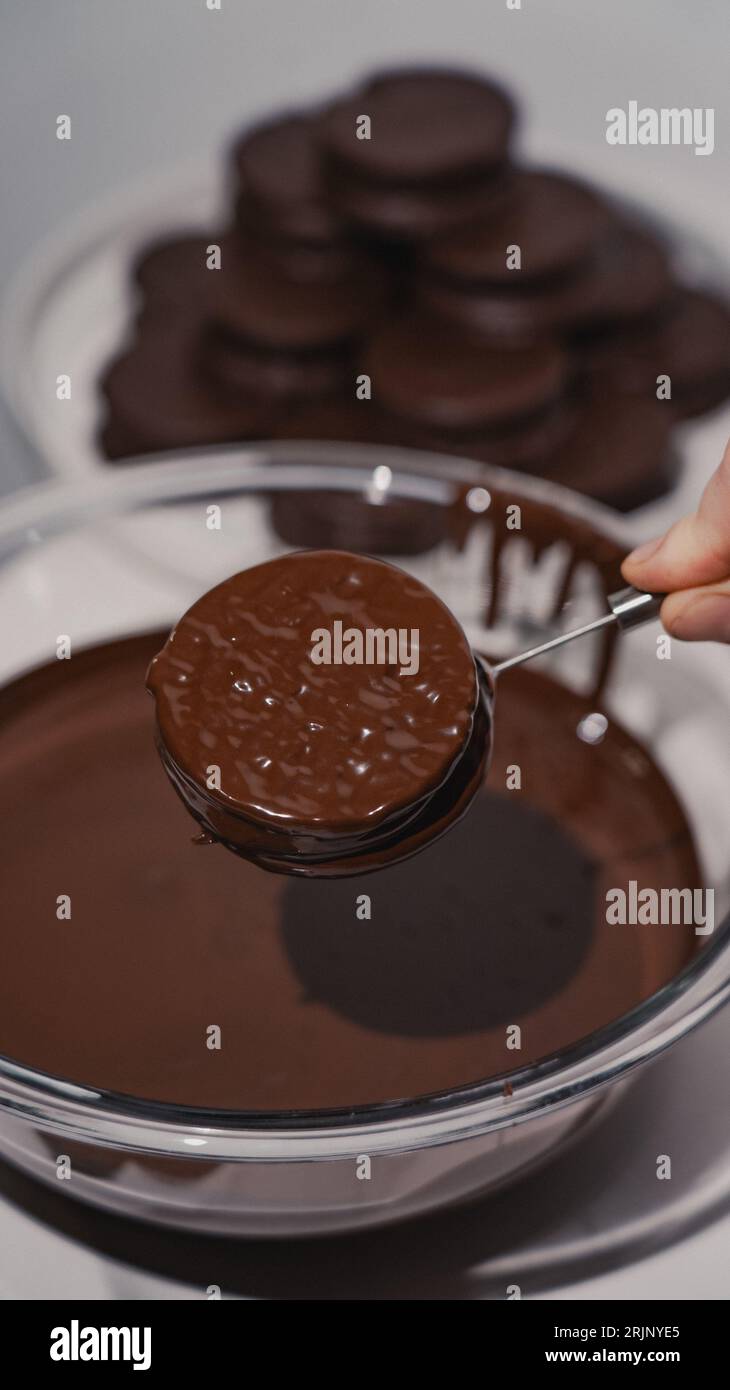 The process of dipping a cookie into a bowl of melted chocolate Stock ...