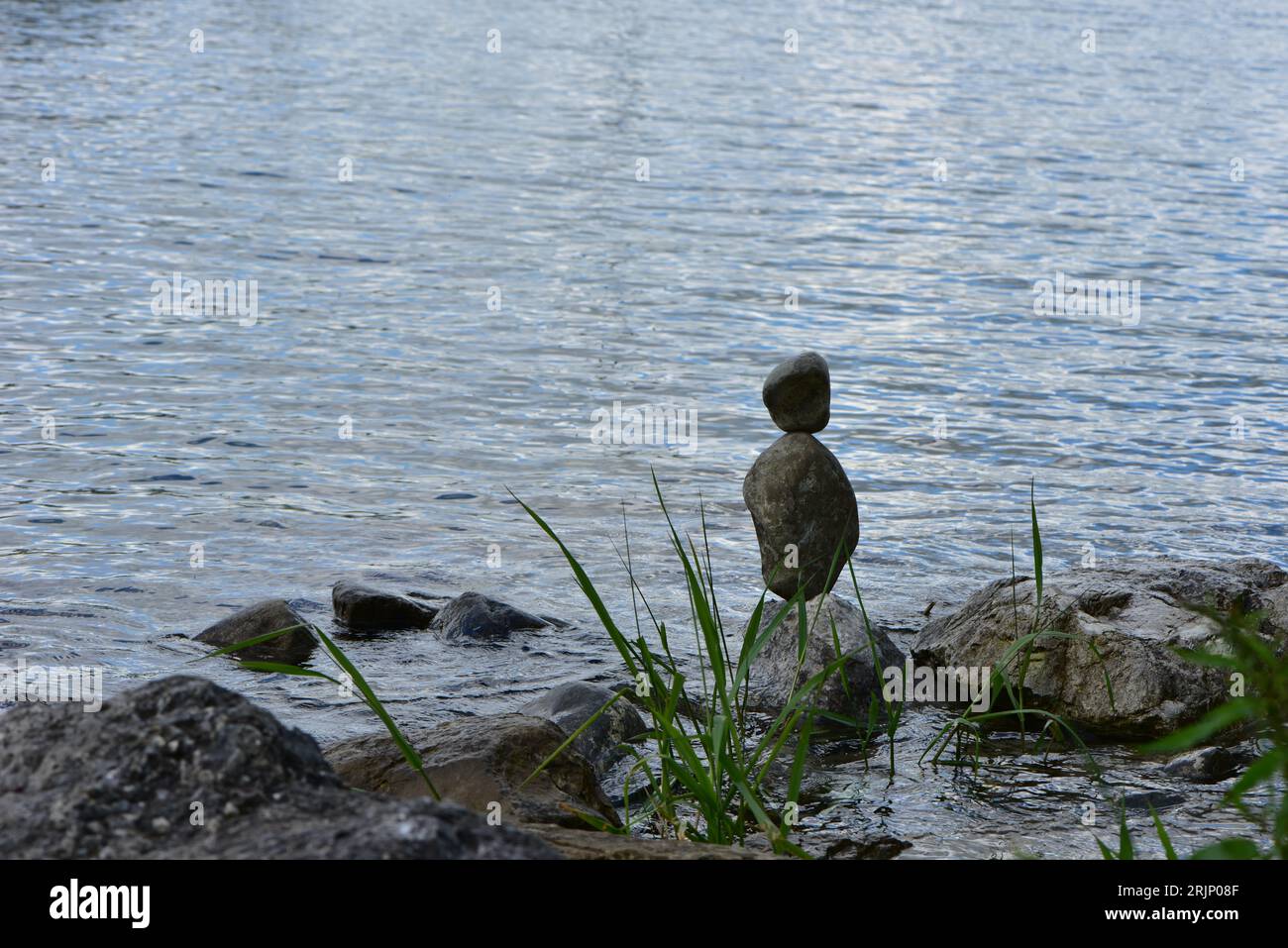 The balanced rocks on each other at the rocky shoreline of a calm body ...