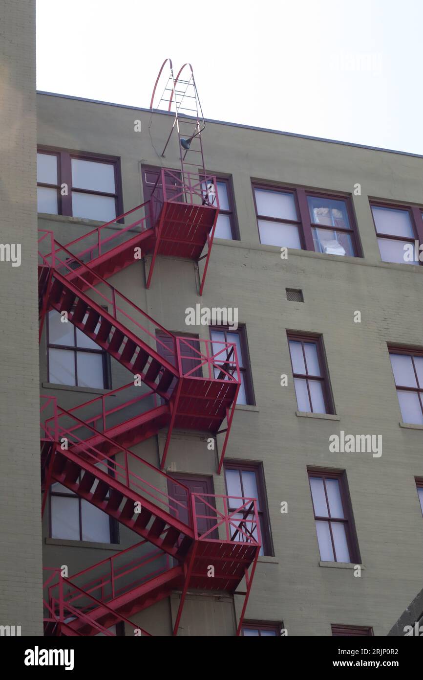 A red iron fire escape staircase leading to a second story window ...