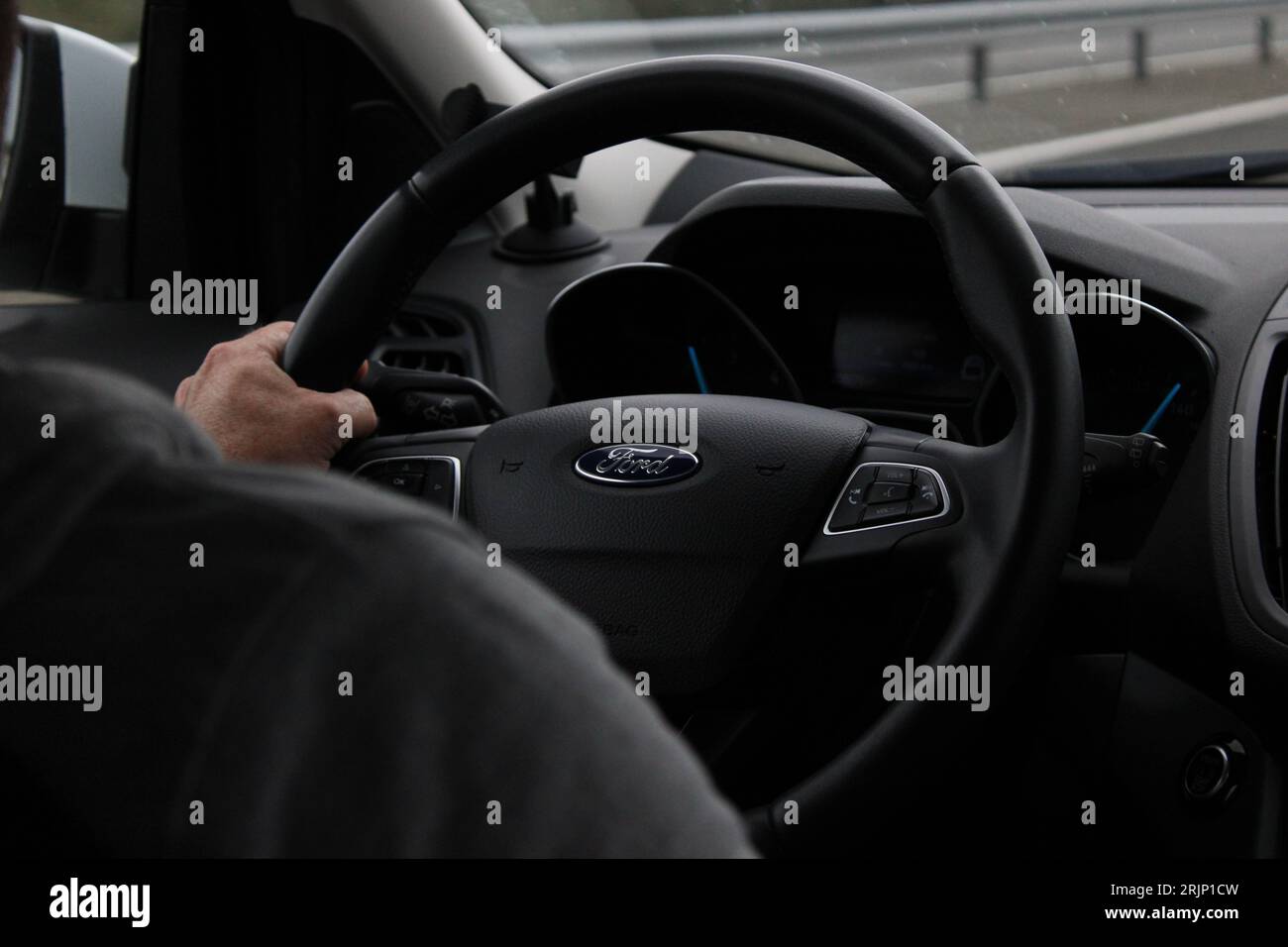 A person driving a Ford vehicle down a city street, featuring a black ...