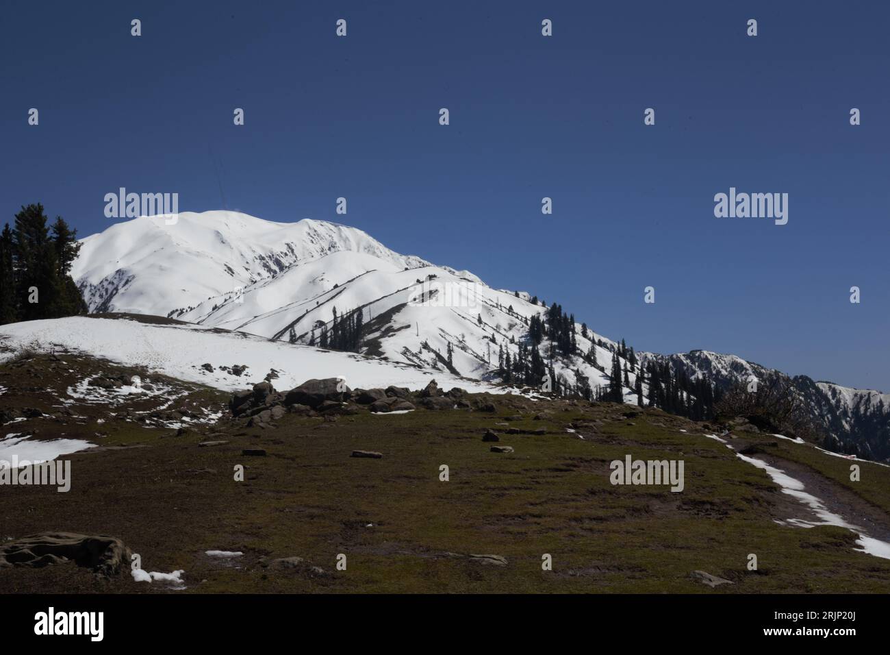 A winter landscape featuring a snowy hill with a winding trail leading ...