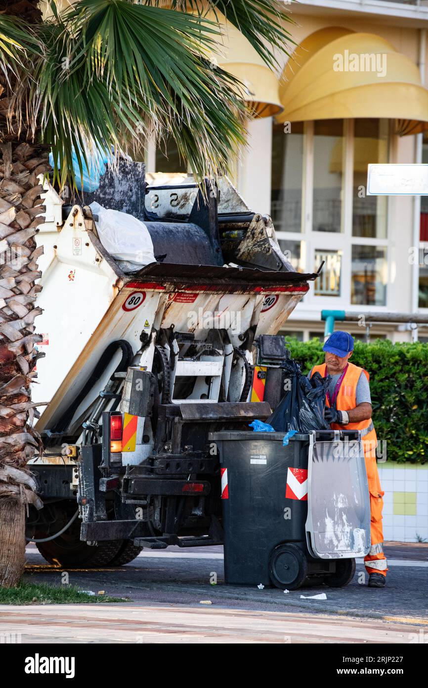 garbage collector loads garbage on the truck Stock Photo - Alamy