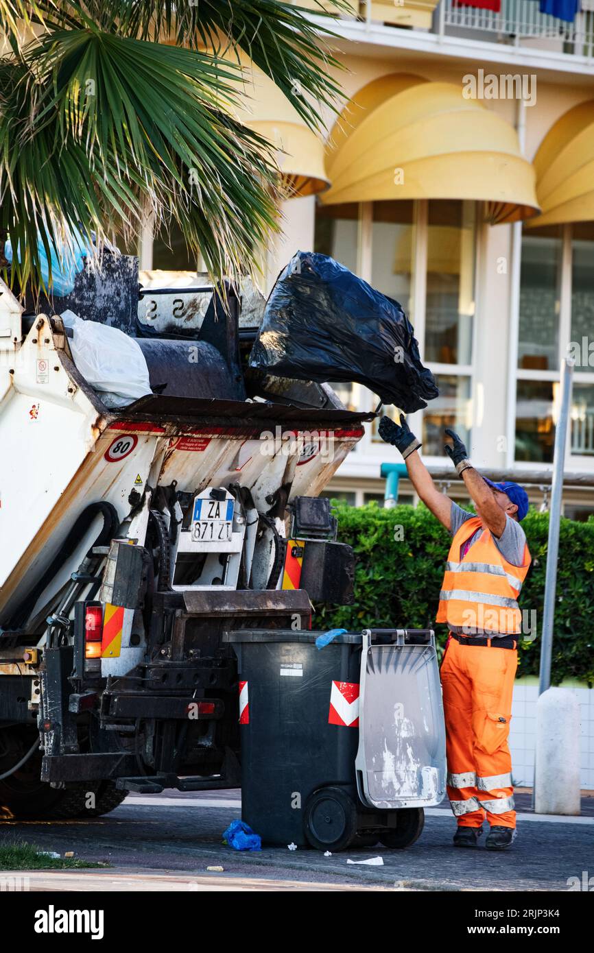 garbage collector loads garbage on the truck Stock Photo - Alamy