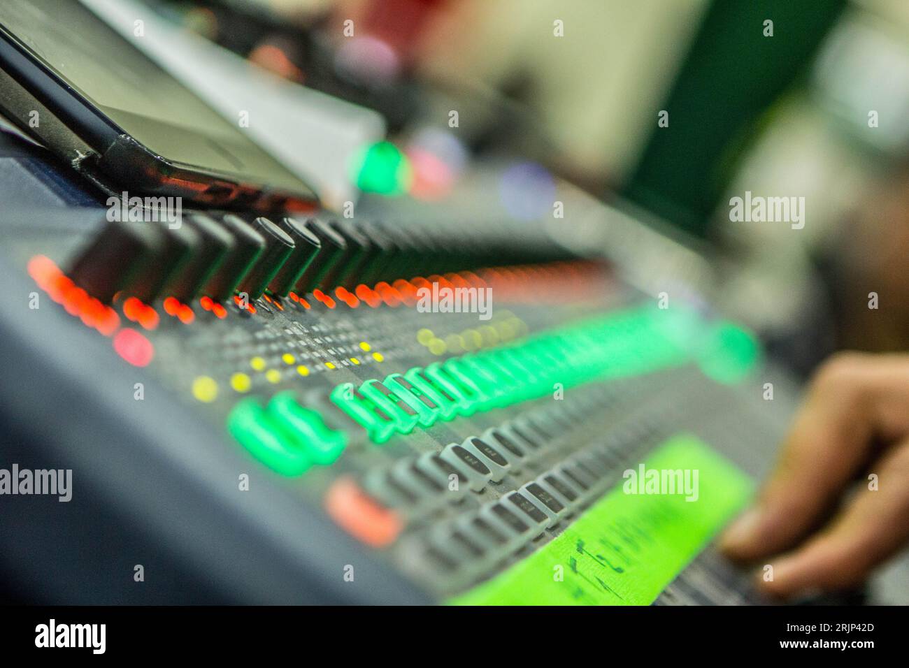 A person operating a mixing desk with their hands making adjustments to ...