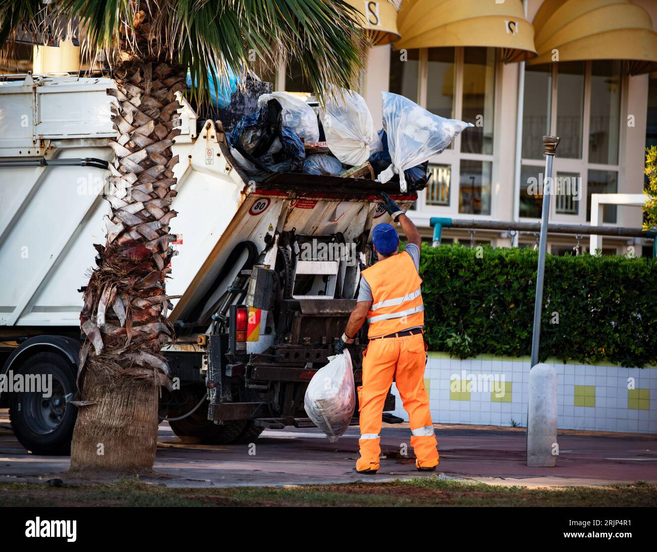 garbage collector loads garbage on the truck Stock Photo - Alamy