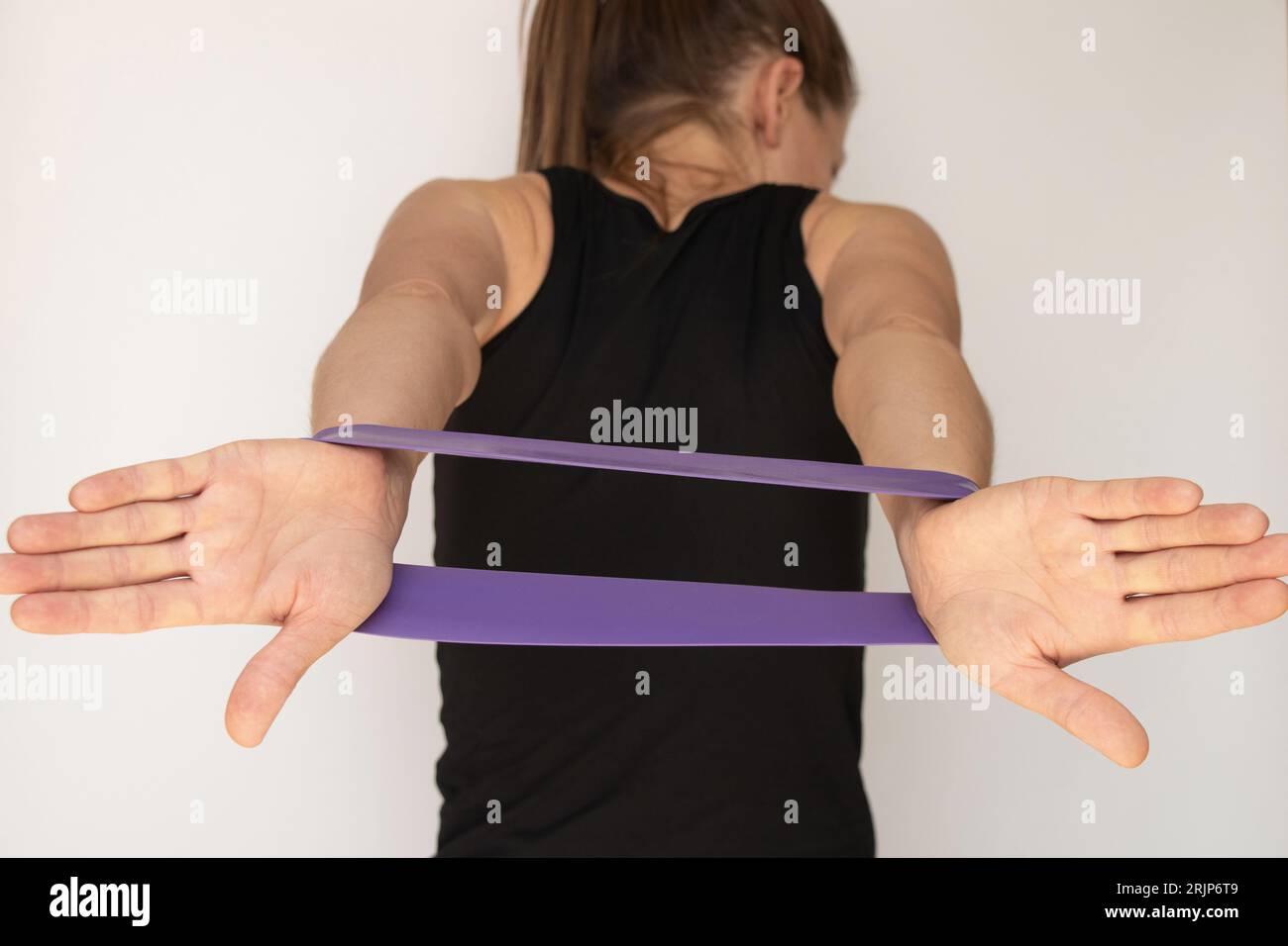 The girl is engaged in fitness with a fitness rubber band on a white ...