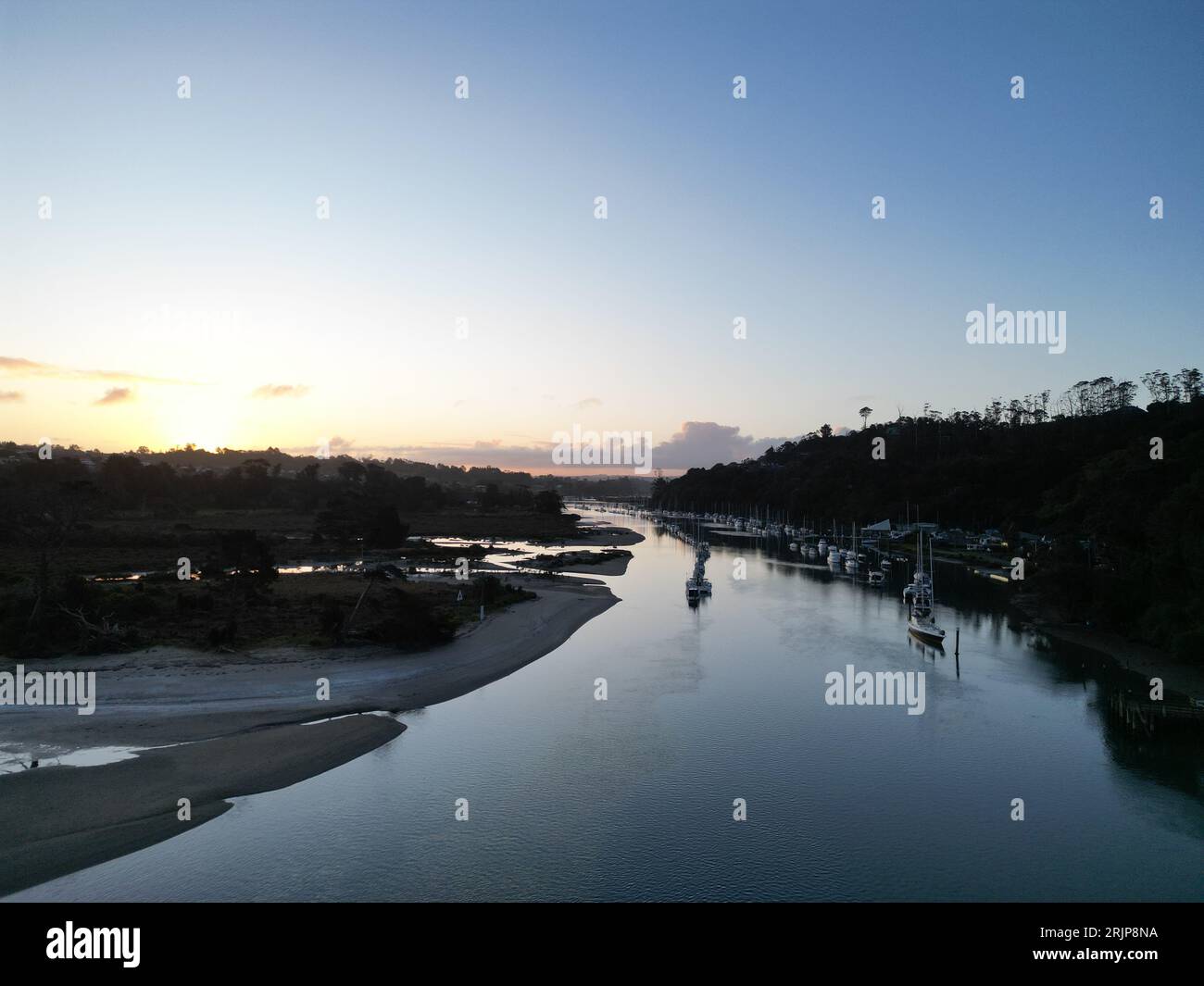 A moody evening scene of boats and houses amongst the Weiti River ...