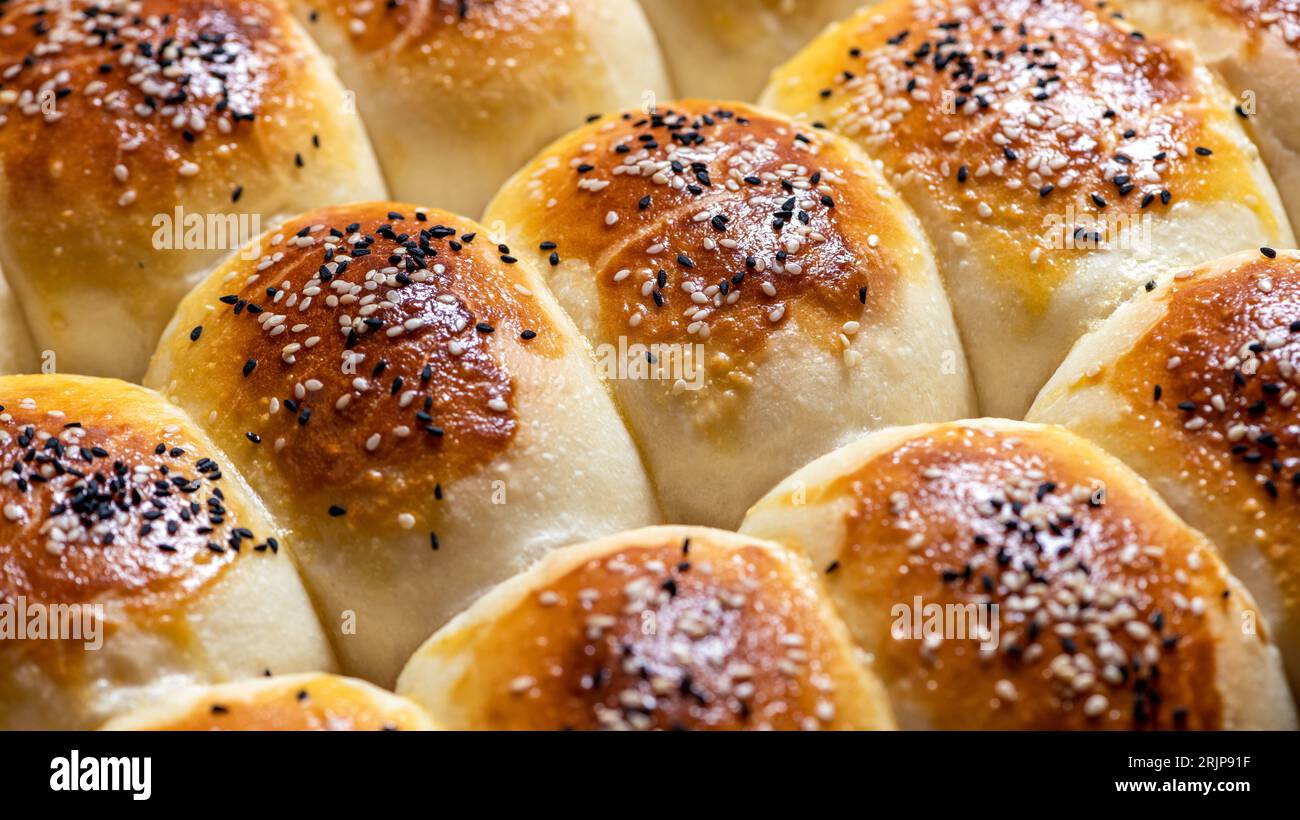 A closeup of a freshly baked batch of soft pastry buns in an oven tray ...