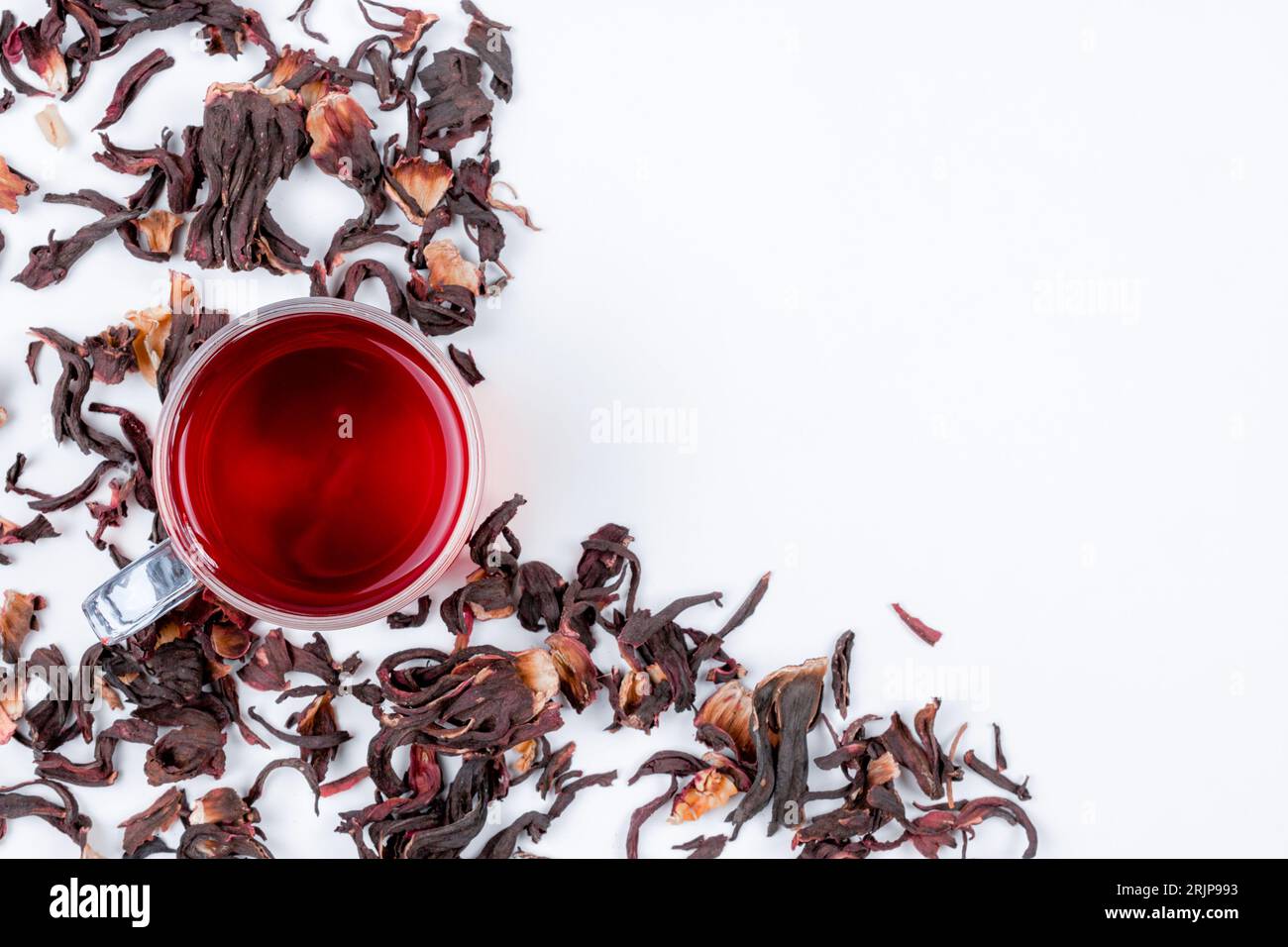 A glass cup filled to the brim with a vibrant red hibiscus tea, with a ...