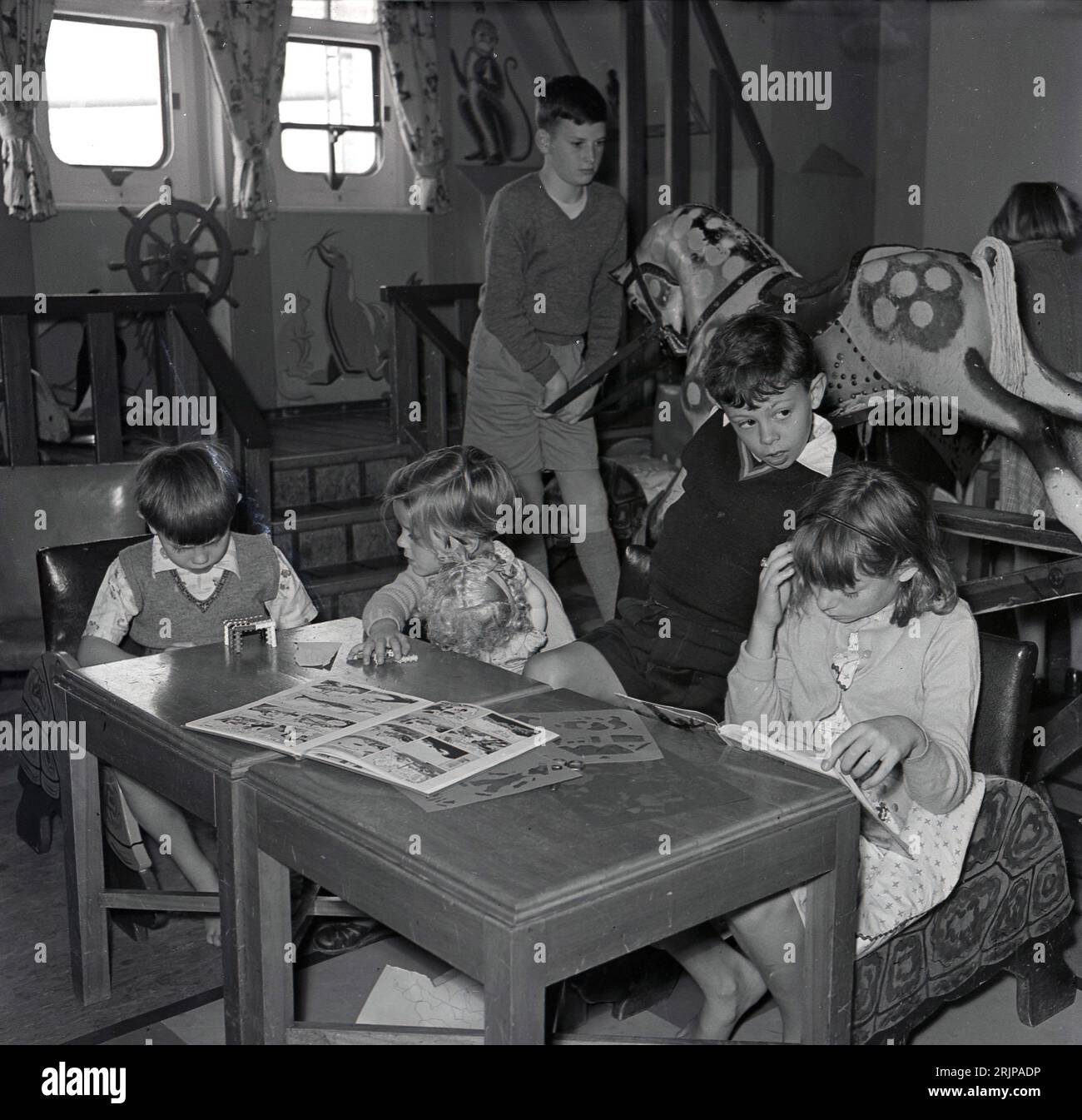 1950s, historical, child passengers sitting reading picture books in ...