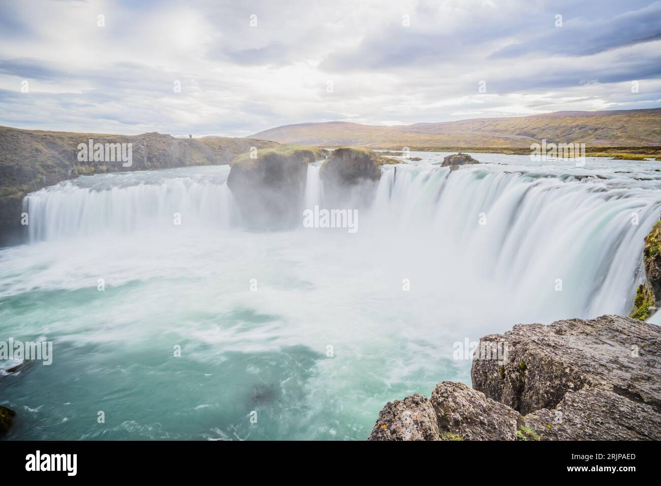 A scenic view of a waterfall cascading down a rocky ravine, set against ...