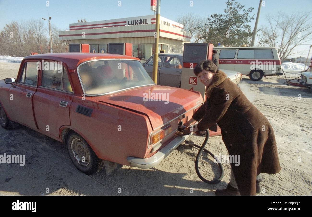 Volgograd, Russia - January 1996: Scanned film image, Woman fuels a car ...