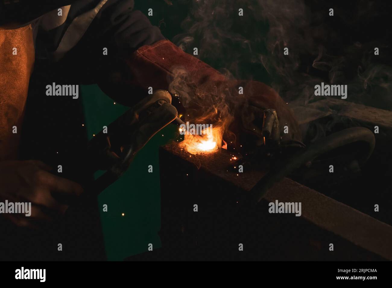 A close-up of a welder connecting two metal pieces together Stock Photo ...