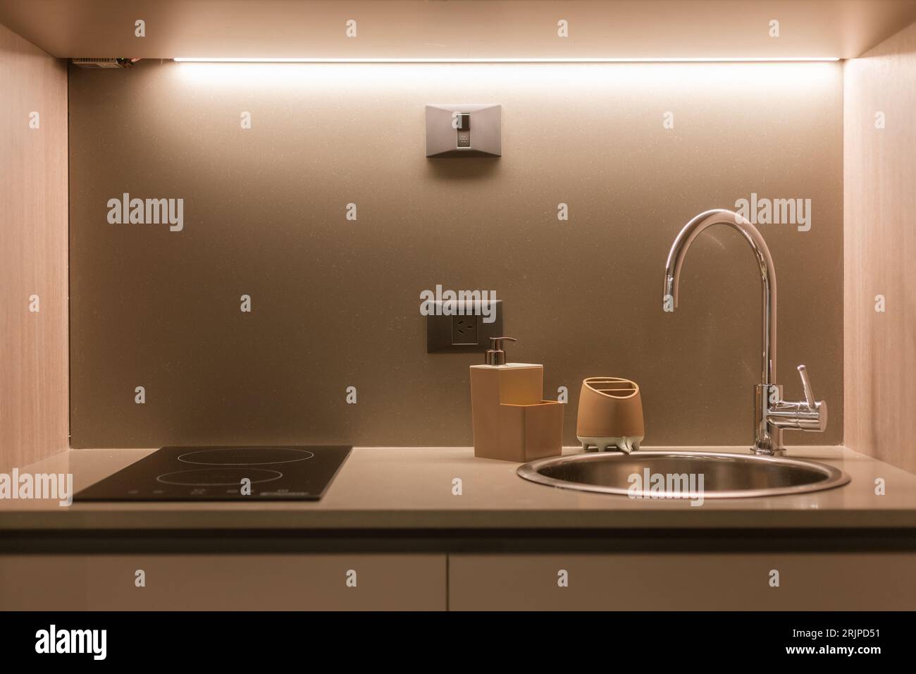 A contemporary kitchen with light fixtures overhead the stovetop and a ...