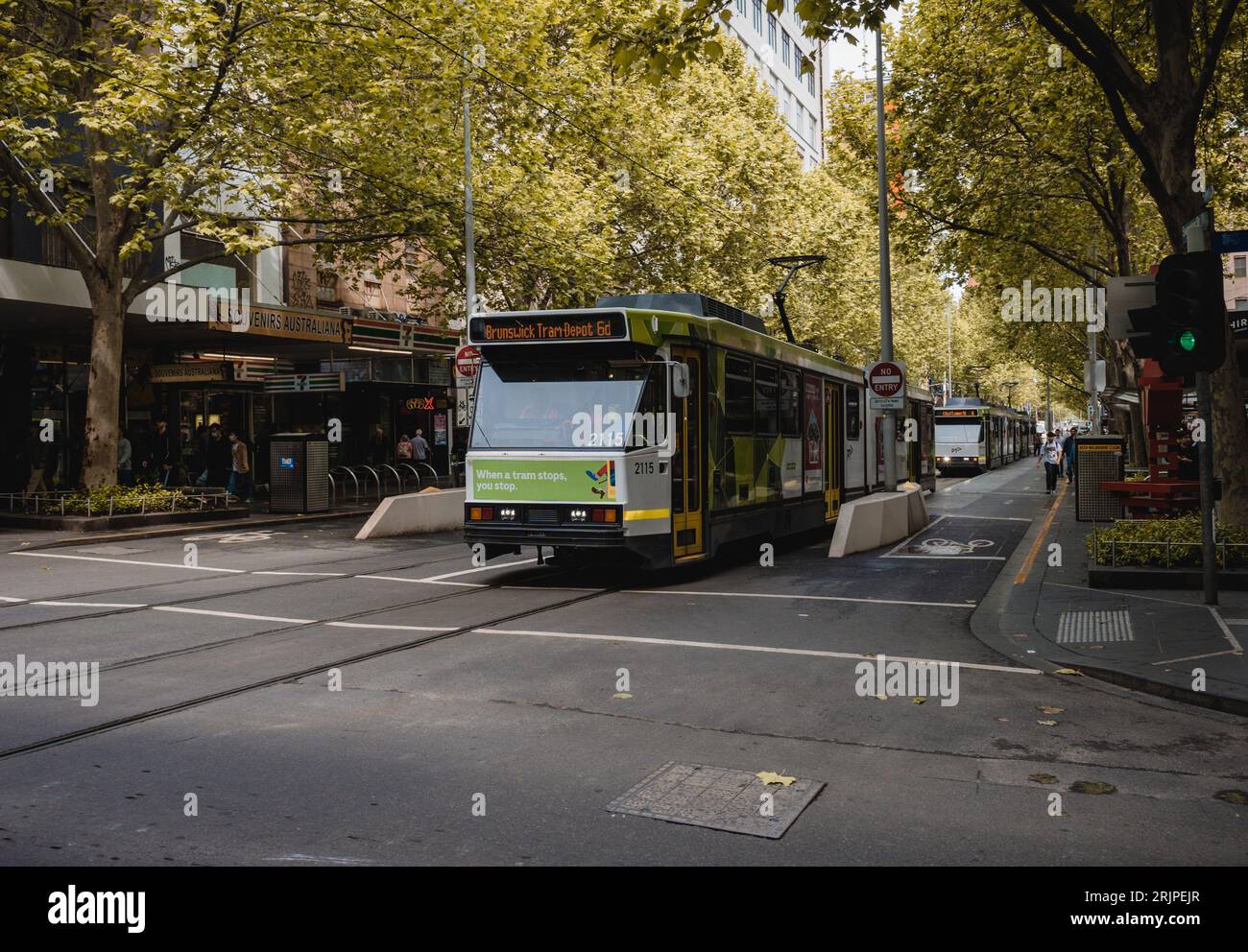 A public green city bus traveling along a picturesque street in ...