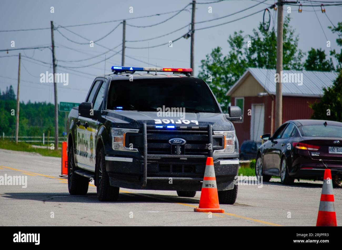 A silver police car parked on the street in front of a series of orange ...