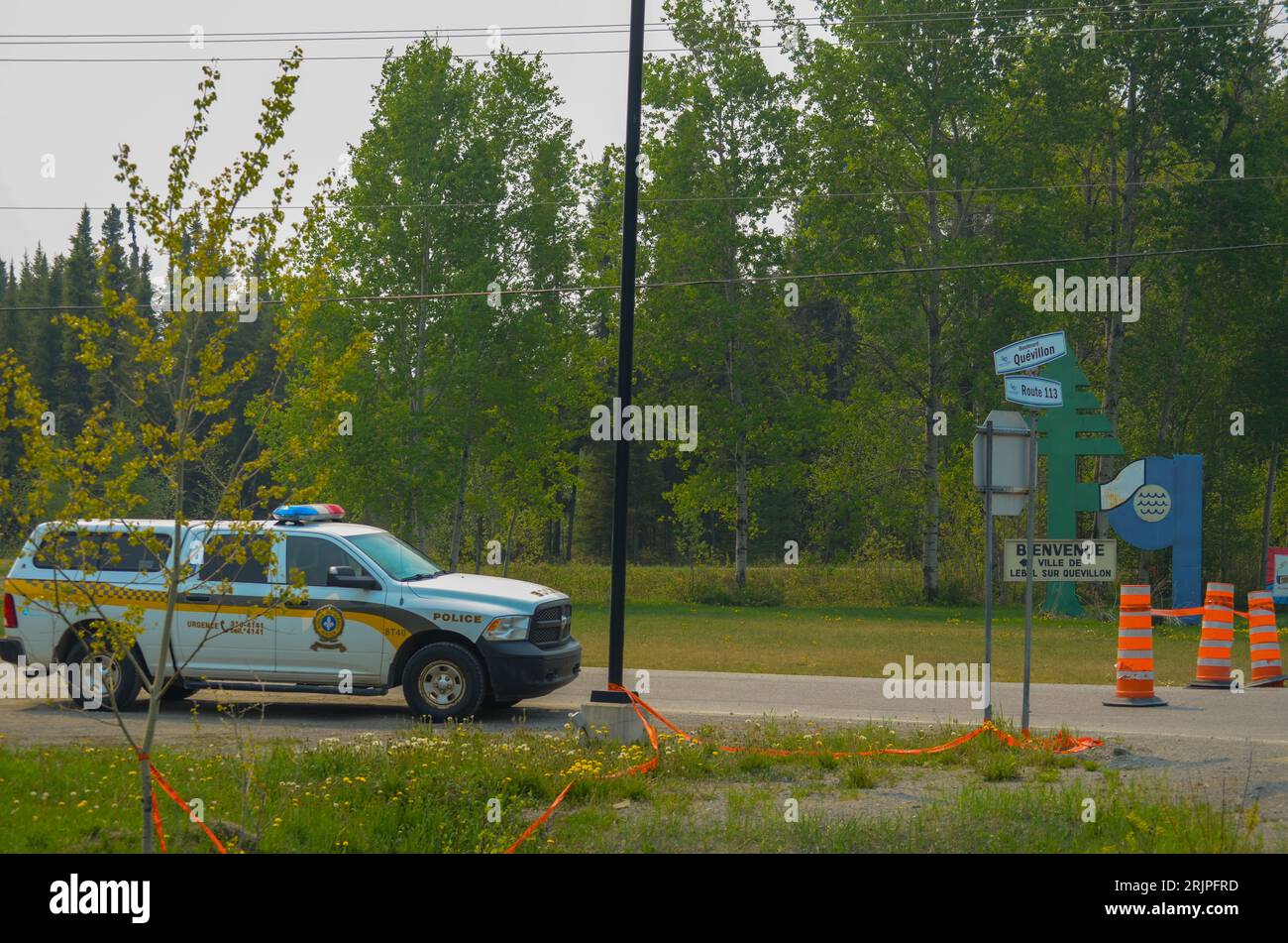 A silver police car parked on the street in front of a series of orange ...