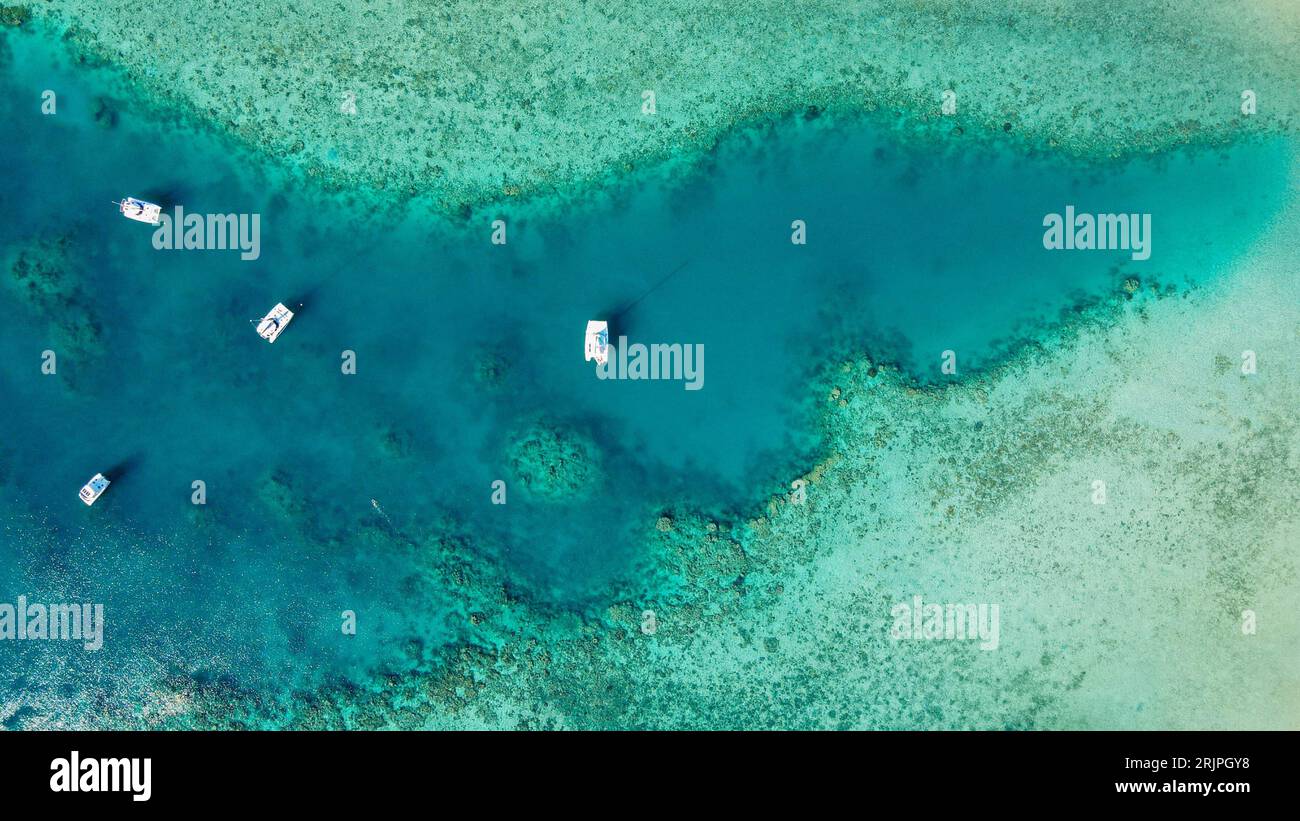 An aerial view of several boats peacefully floating in the pristine ...