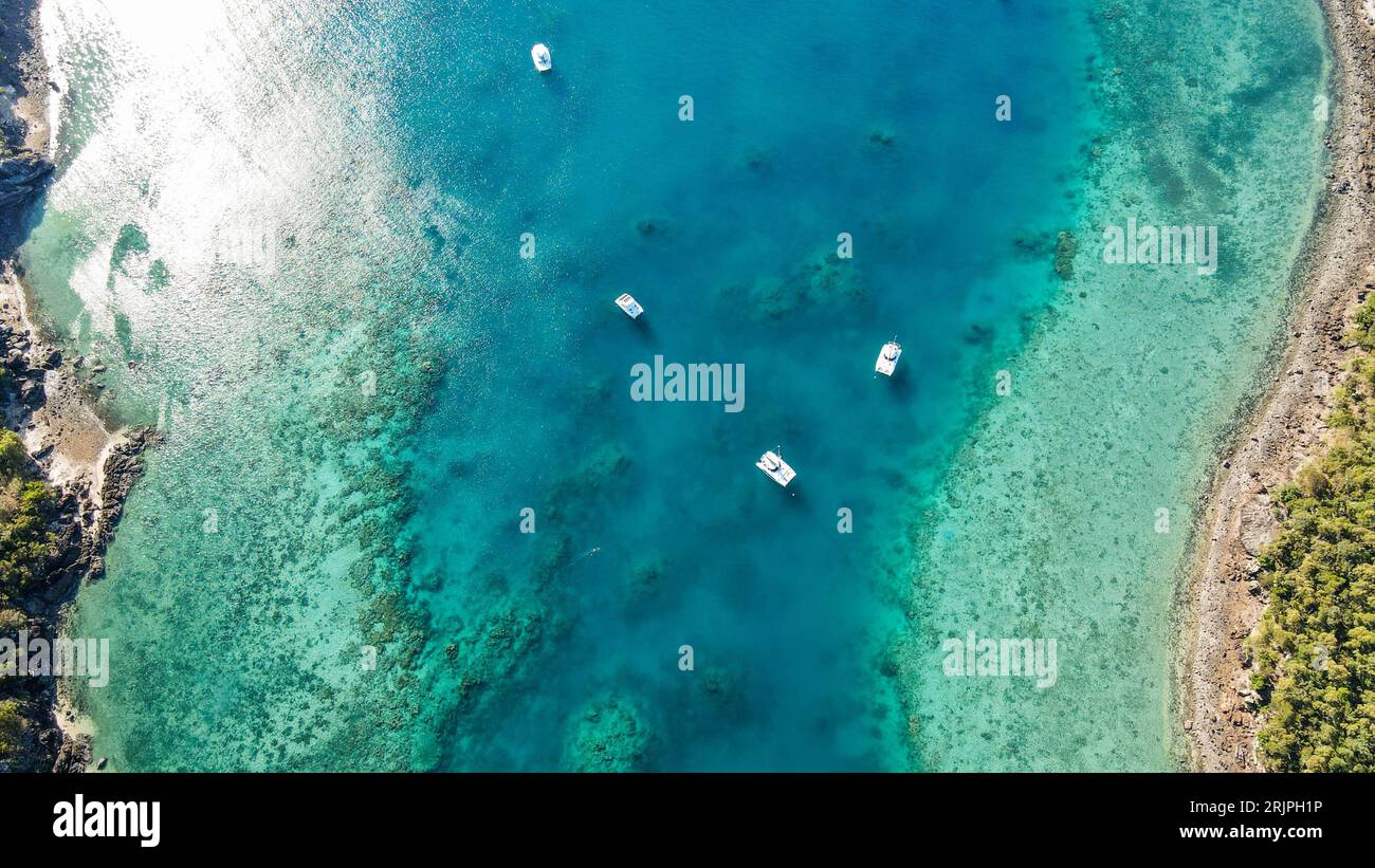 An aerial view of several boats peacefully floating in the pristine ...
