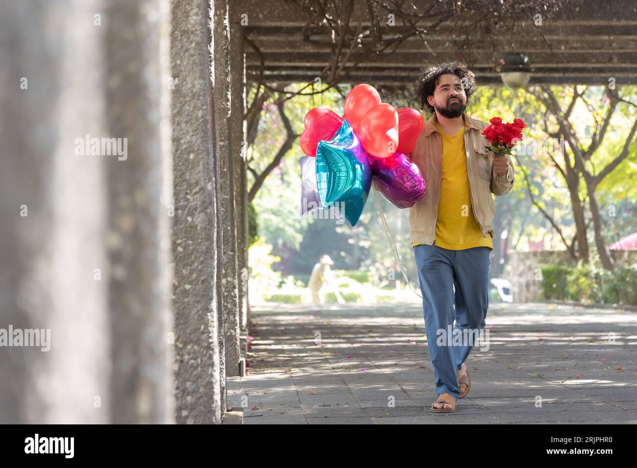 A young man joyfully walking through an alleyway carrying a bundle of ...