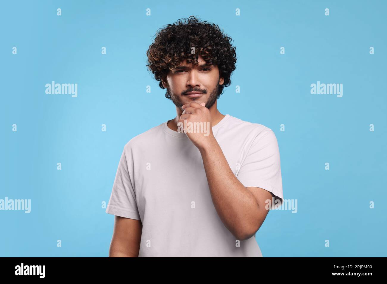 Handsome thoughtful man on light blue background Stock Photo - Alamy