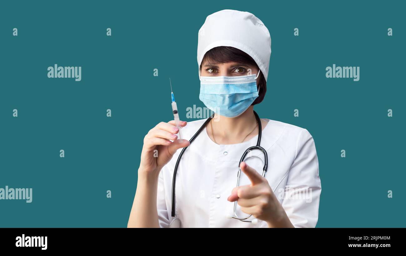 Doctor with a syringe with an injection points his finger at the camera ...