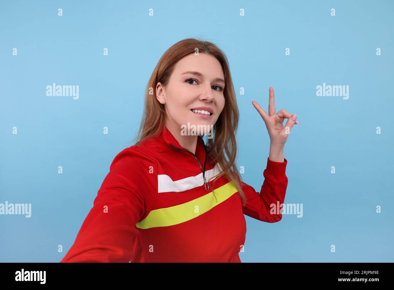 Beautiful woman taking selfie on light blue background Stock Photo - Alamy