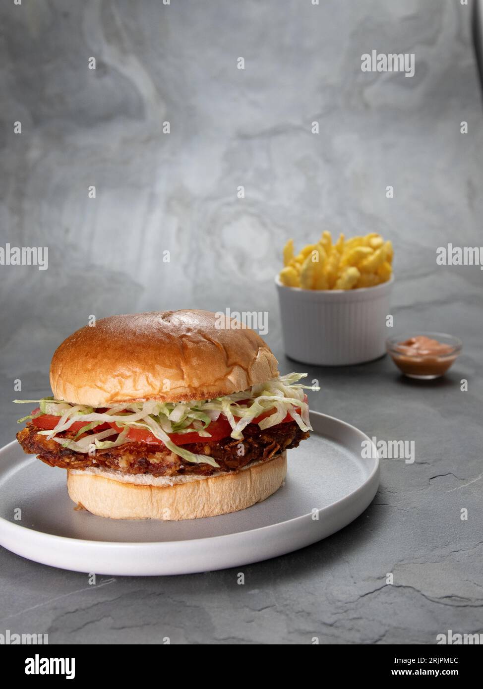 A closeup of a Crispy chicken fillet burger served with French fries on ...