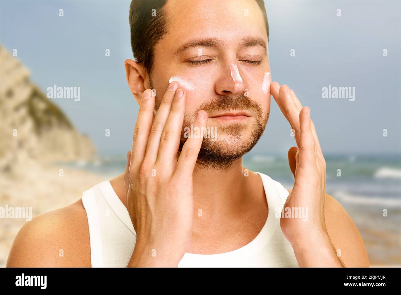 Sun protection. Man applying sunblock onto face on beach Stock Photo ...