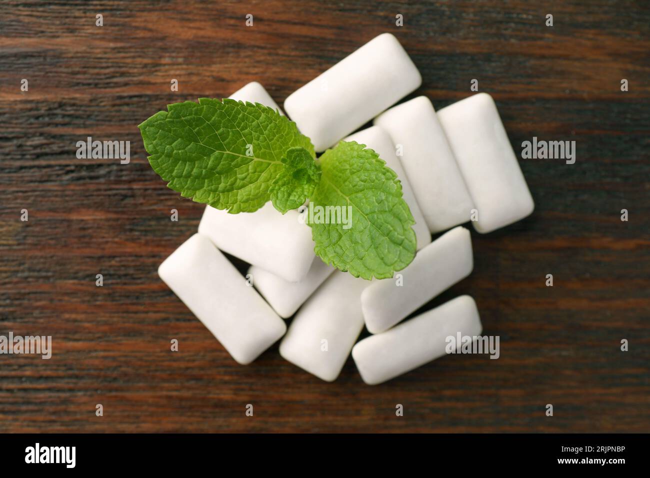 Tasty white chewing gums and mint leaves on wooden table, top view ...