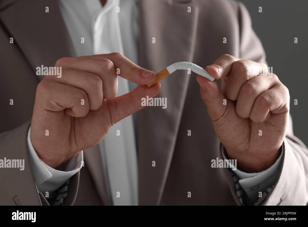 Stop smoking concept. Man breaking cigarette on gray background ...