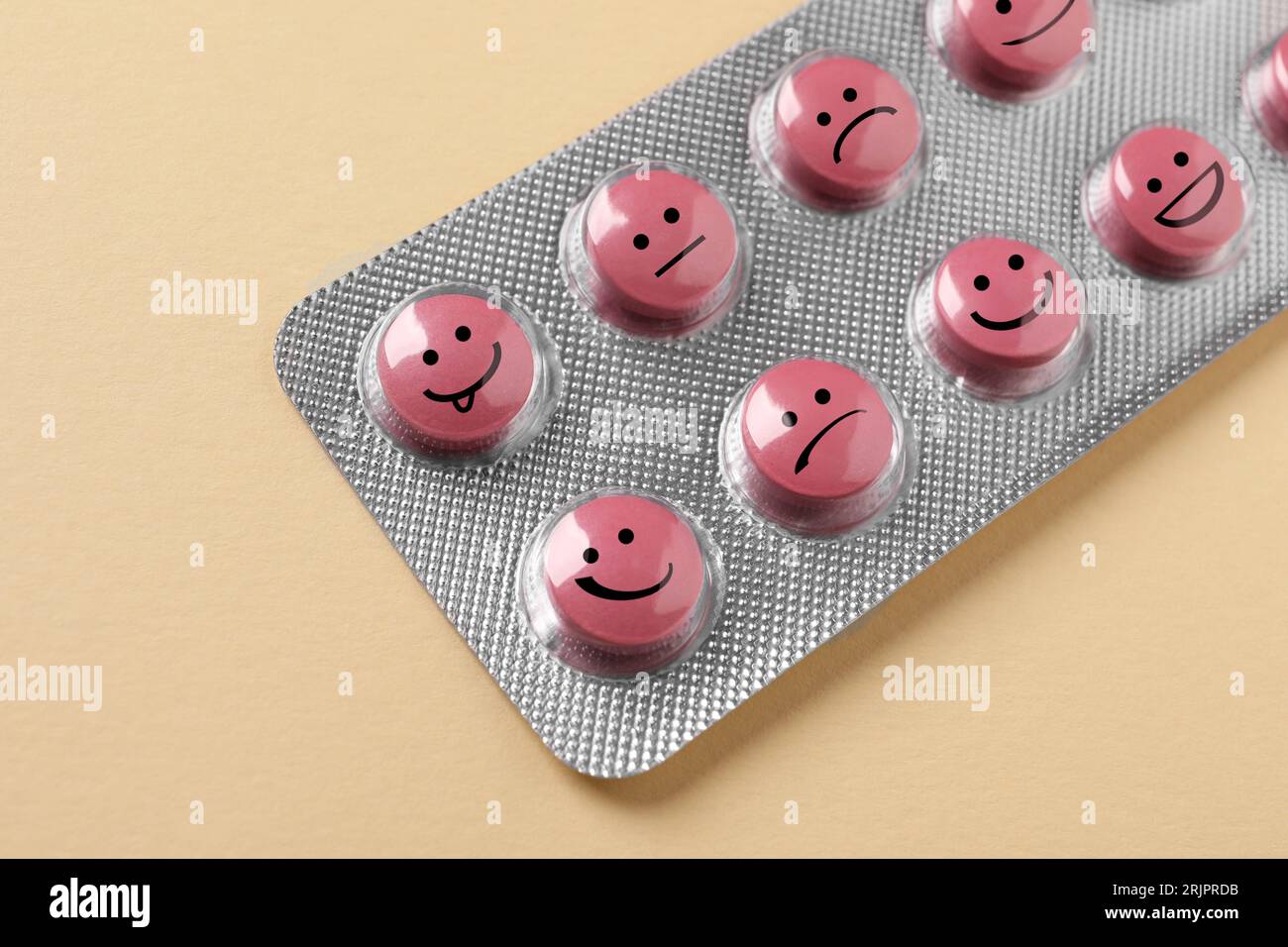 Pink pills with different emotional faces in blister on beige ...